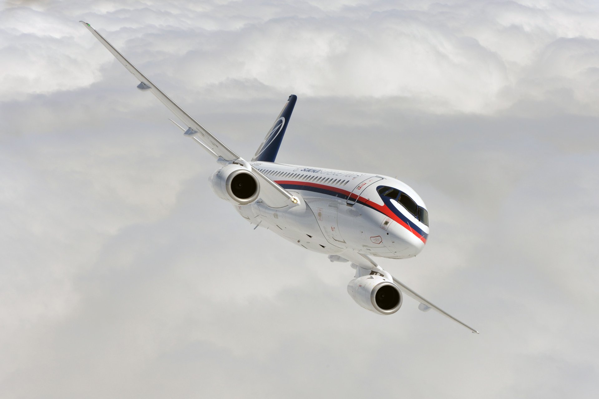 Sukhoi SuperJet 100 Soaring Above the Clouds – HD Flight Wallpaper